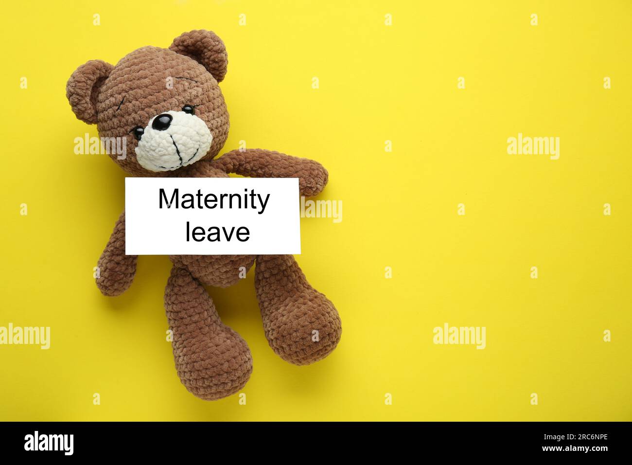 Toy bear and note with words Maternity Leave on yellow background, top ...