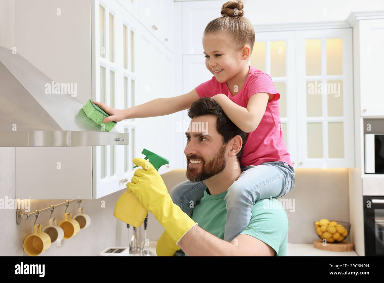 Spring cleaning. Father and daughter tidying up in kitchen together ...