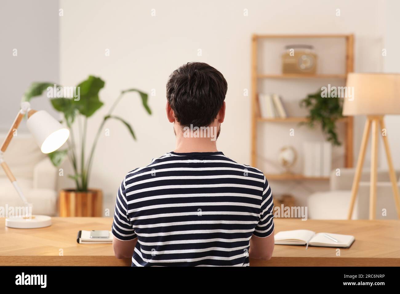 Home workplace. Man working at wooden desk in room, back view Stock ...