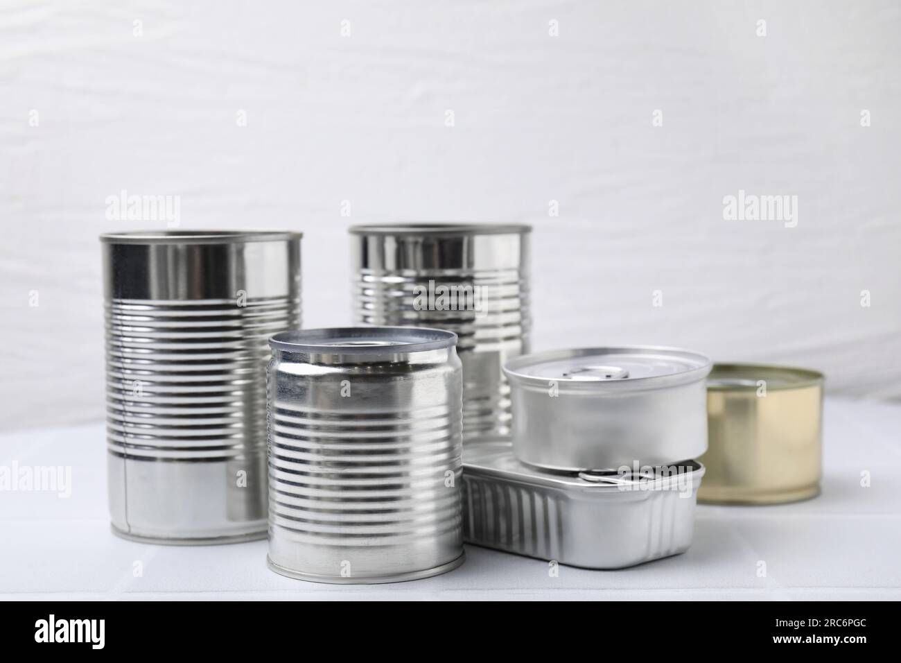 Many closed tin cans on white tiled table Stock Photo - Alamy