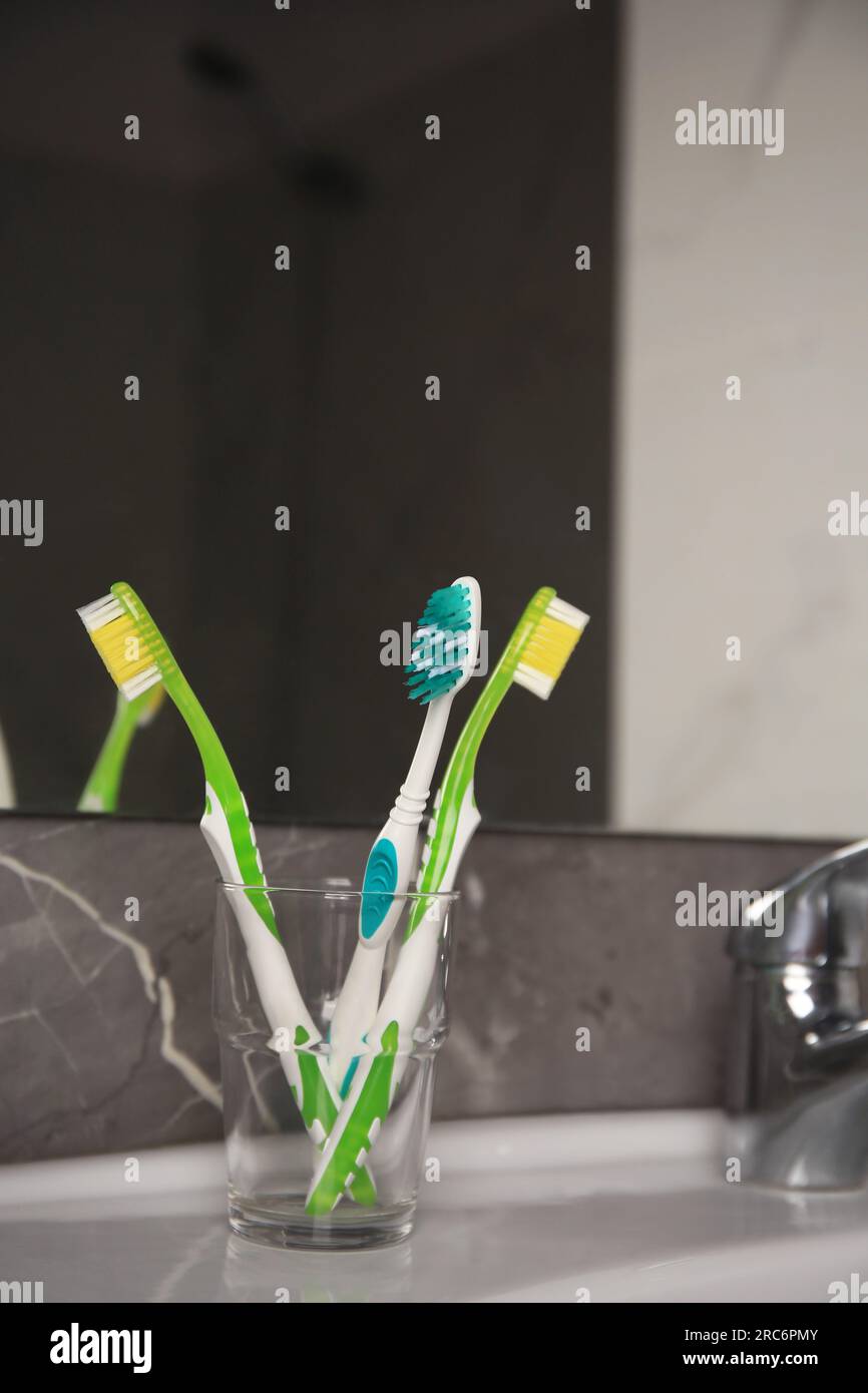Light blue and green toothbrushes in glass holder on washbasin Stock ...
