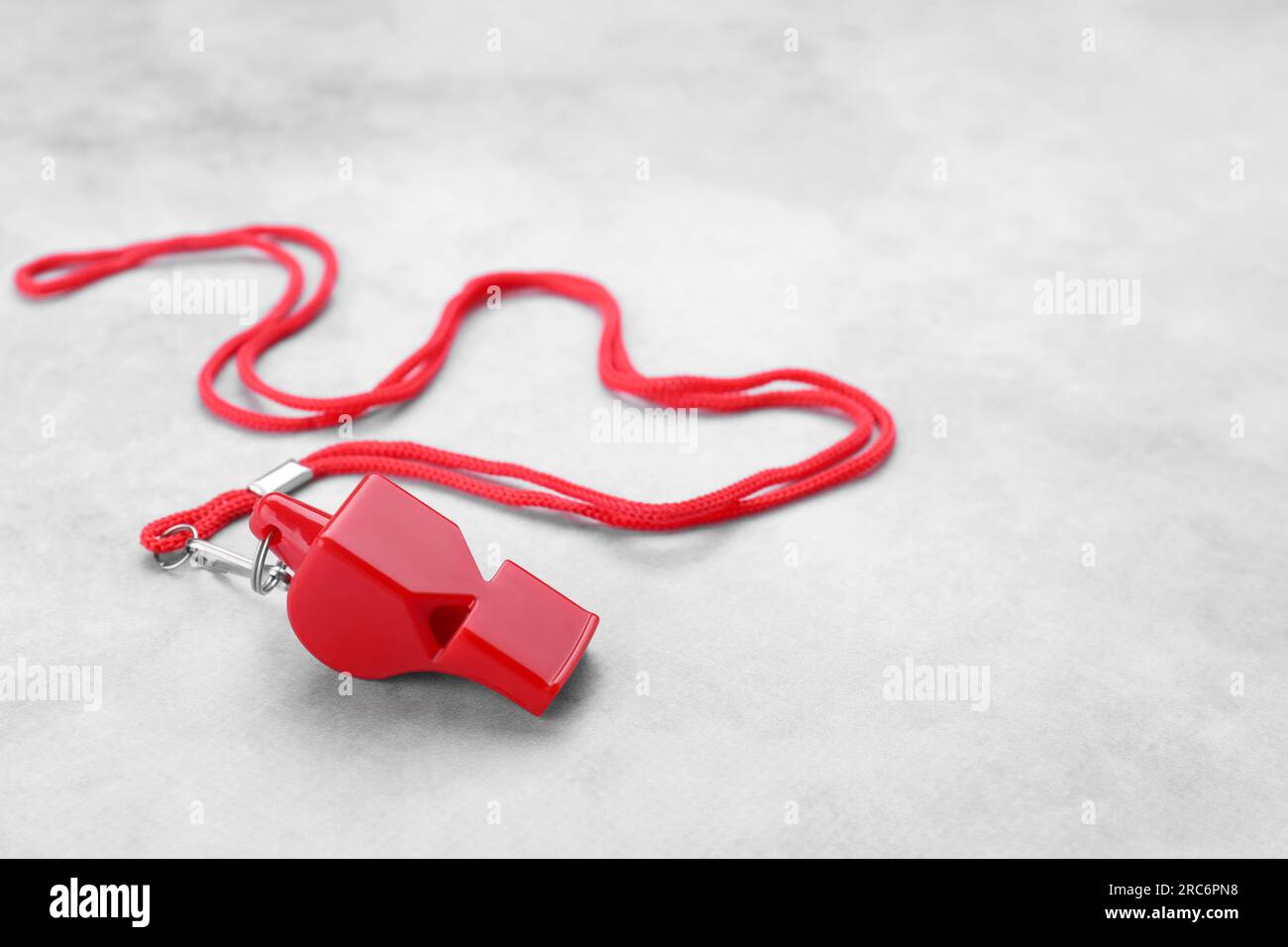 One red whistle with cord on light grey table. Space for text Stock ...