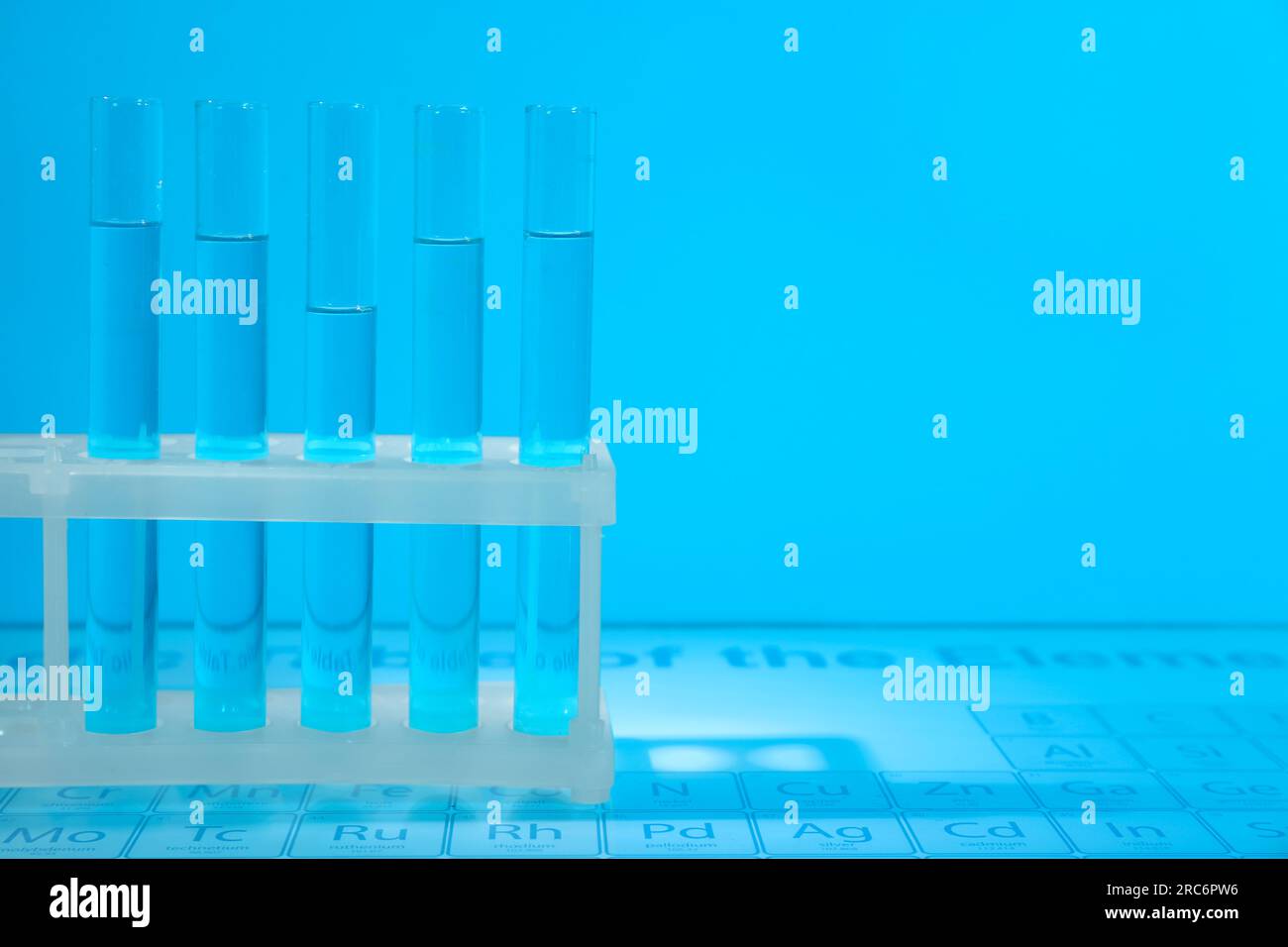 Test tubes on periodic table of elements, toned in light blue. Space ...