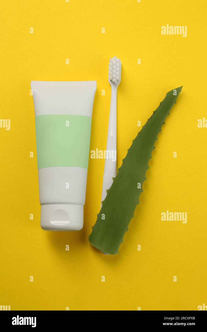Aloe vera toothpaste in blank tube, brush and green leaf on yellow ...