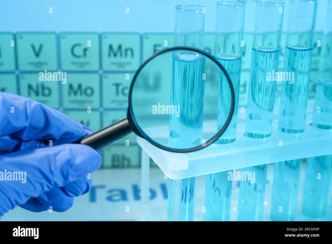 Scientist with magnifying glass examining test tube against periodic ...