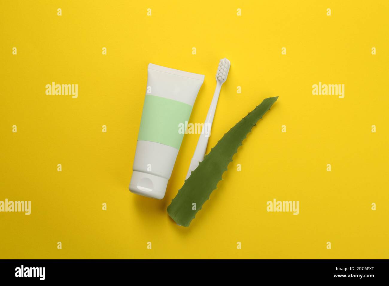 Aloe vera toothpaste in blank tube, brush and green leaf on yellow ...