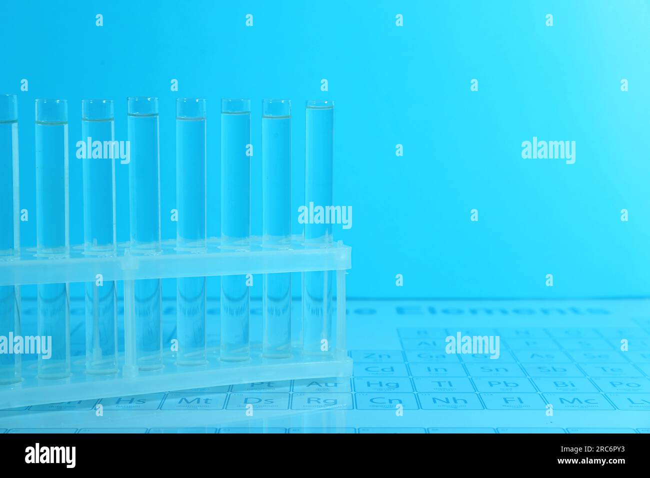 Test tubes on periodic table of elements, toned in light blue. Space ...