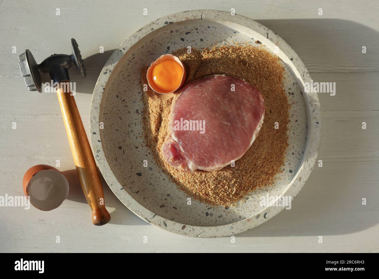 Cooking schnitzel. Raw pork chop, meat mallet and ingredients on white ...