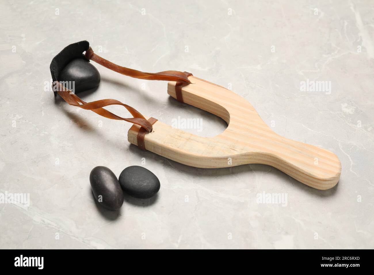 Wooden slingshot with stones on light grey marble background Stock ...