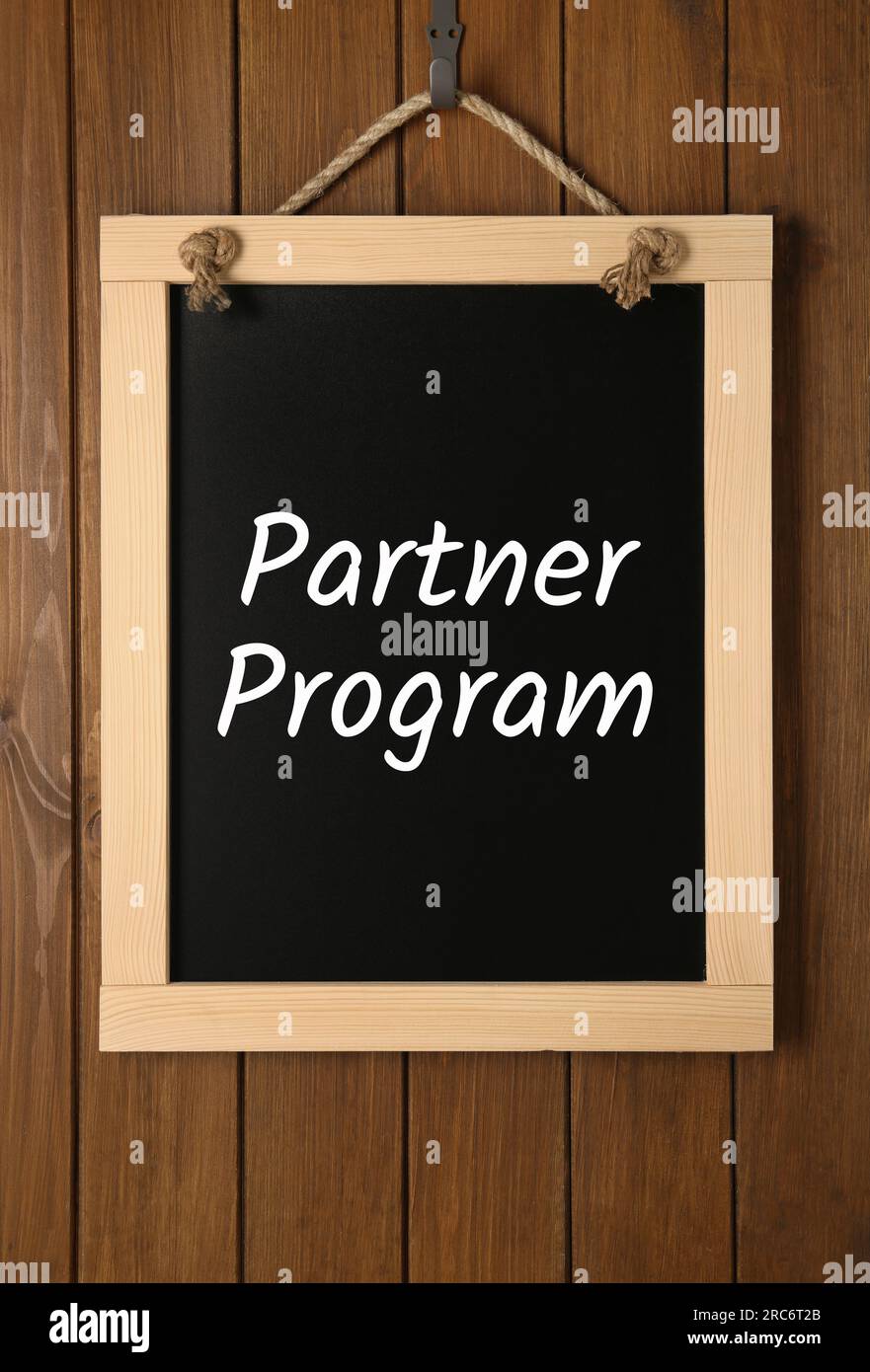 Small black chalkboard with words Partner Program hanging on wooden ...
