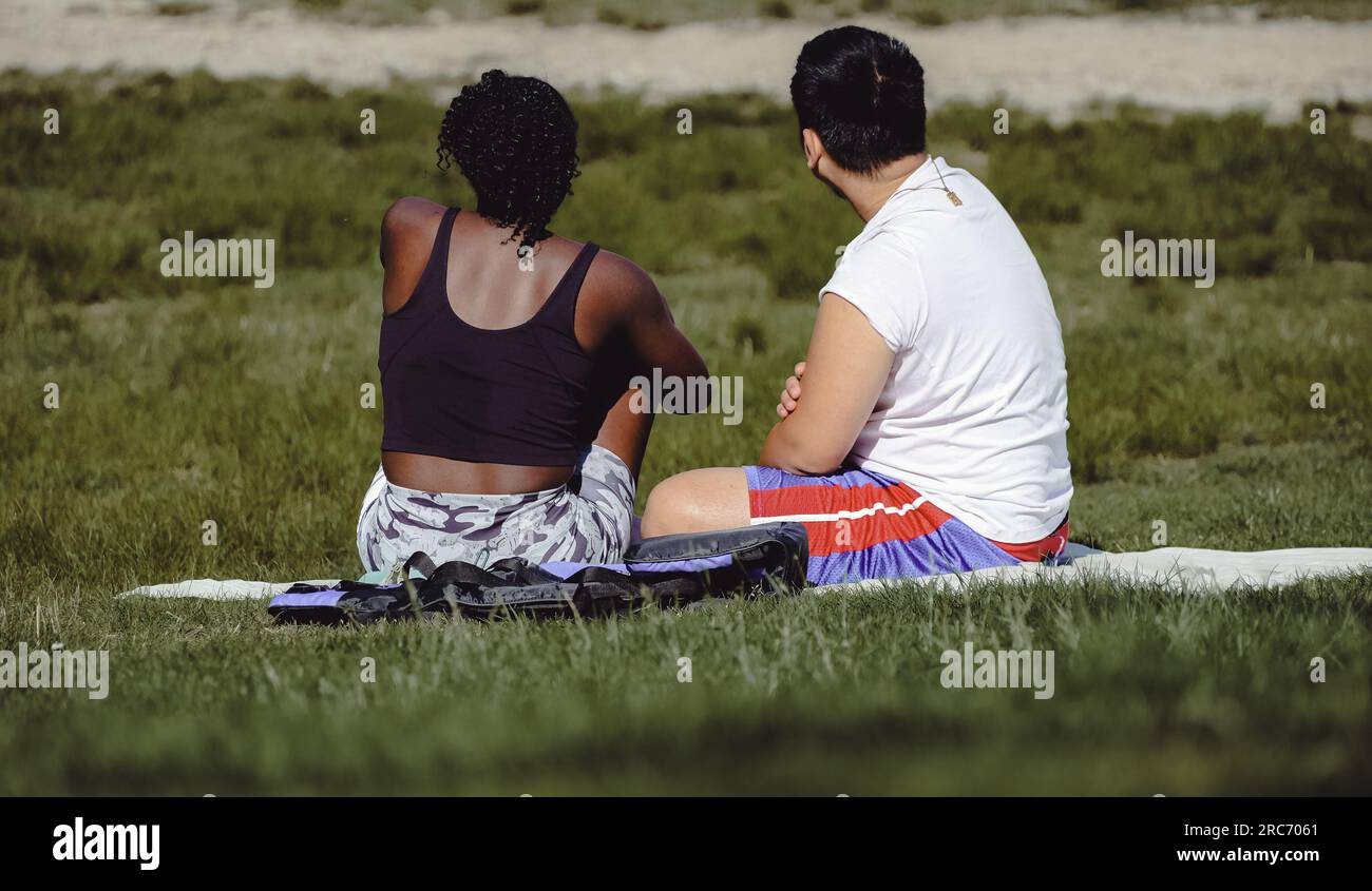 A romantic interracial couple sitting at the beach on a sunny day ...