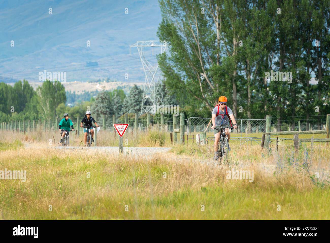 Three cyclists riding the Otago Rail Trail, crossing the intersection ...