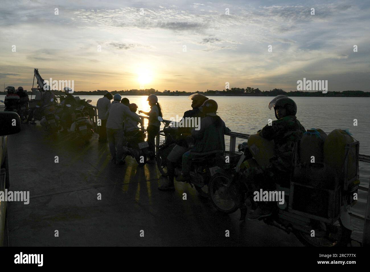 Passengers are silhouetted as they cross the Mekong River from Svay ...
