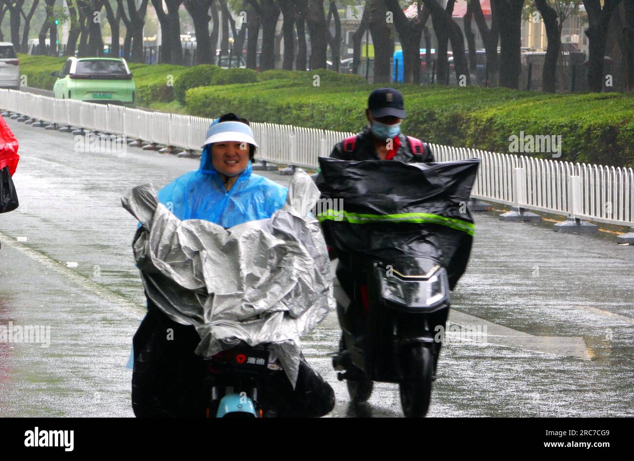BEIJING, CHINA - JULY 13, 2023 - People travel in the rain in Beijing ...