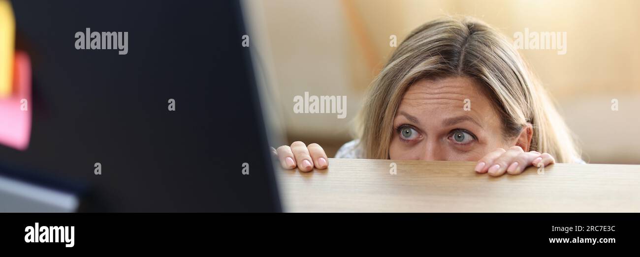Scared and shocked woman in panic behind desk looking at computer ...