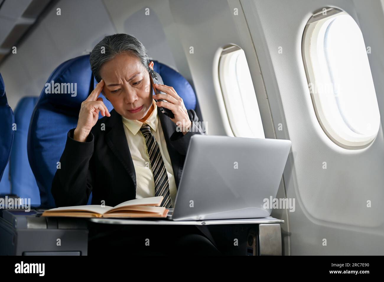 A stressed senior Asian businesswoman or female CEO has a serious phone ...