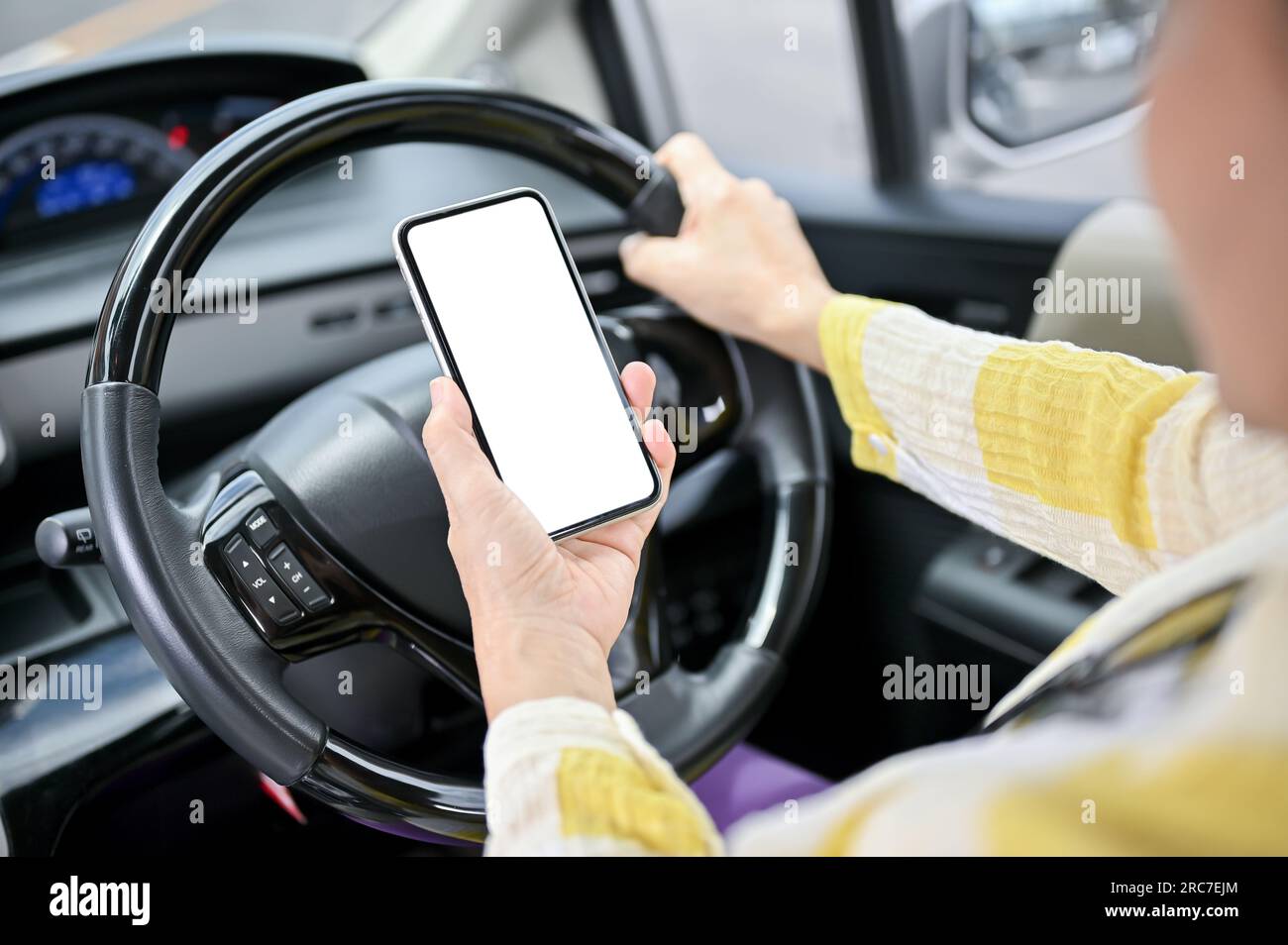Close-up image of an Asian lady using her smartphone while driving a ...