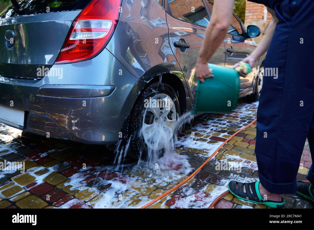 Selective focus. Rear view of a man manually washing his car in the ...