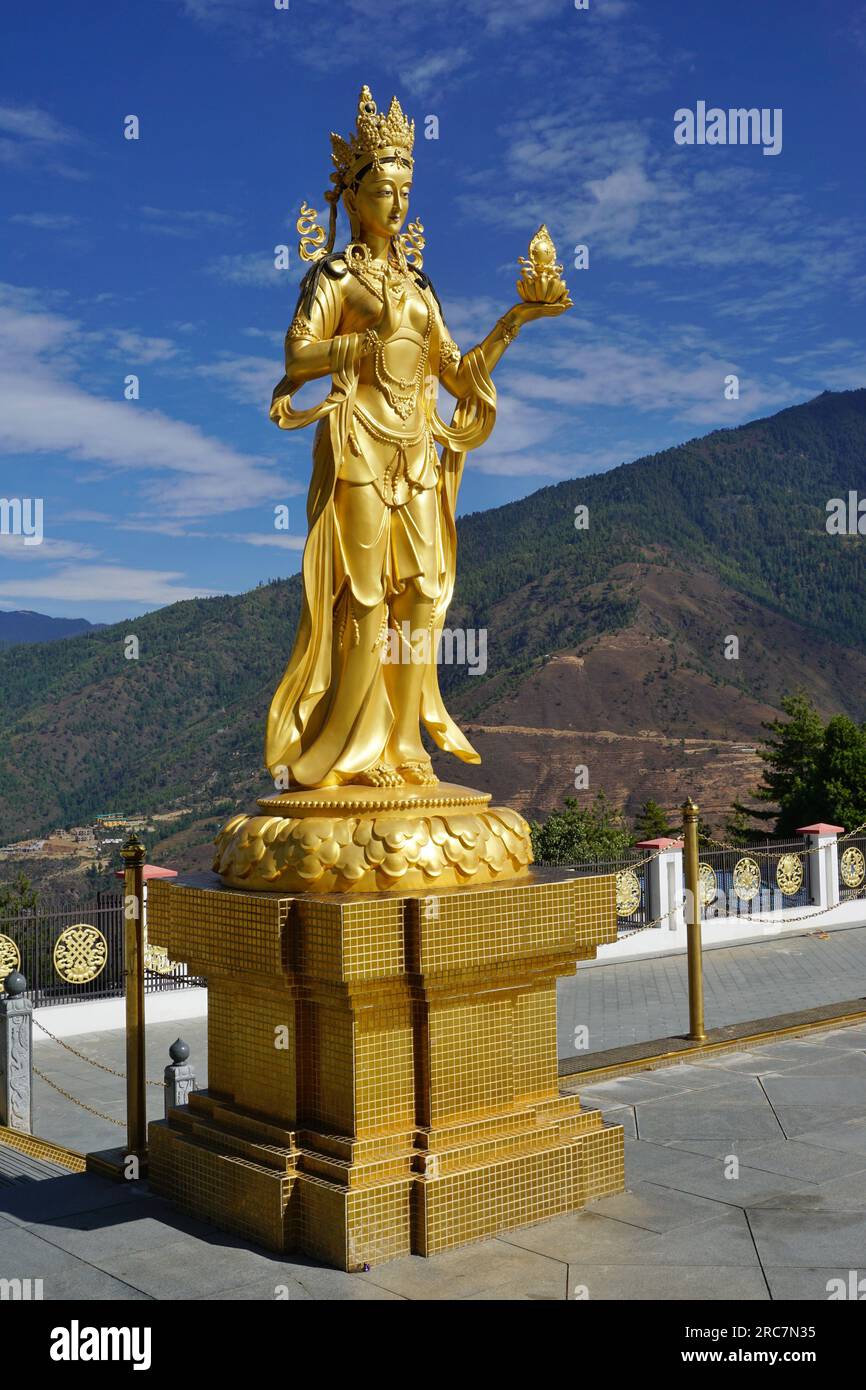 Gilded apsara goddess statue on pedestal in silhouette against blue sky ...