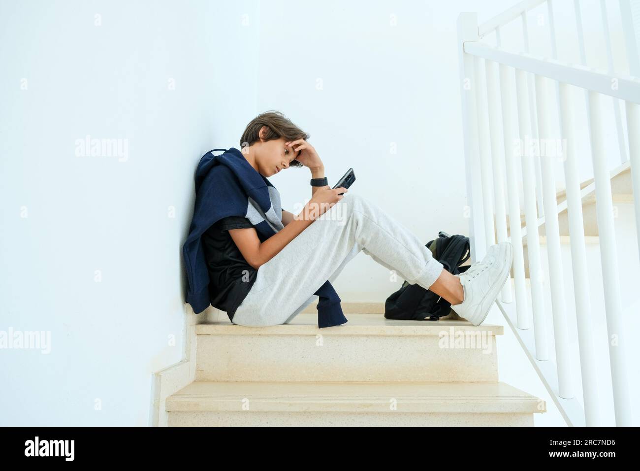 Teenage boy using smartphone. Confused, frustrated teenage boy sitting ...