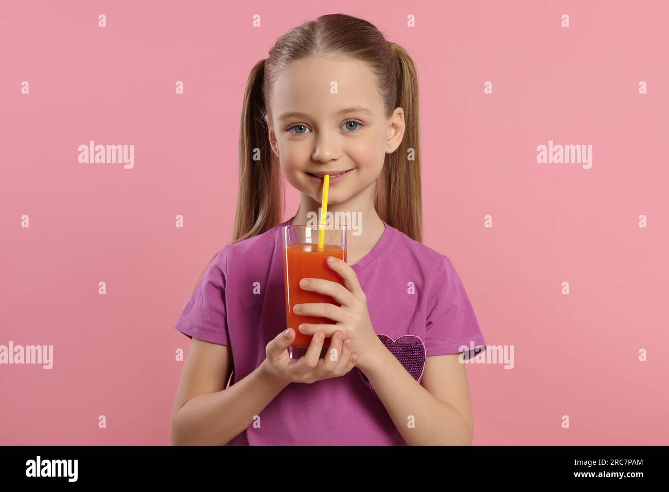 Cute little girl drinking fresh juice with straw on pink background ...