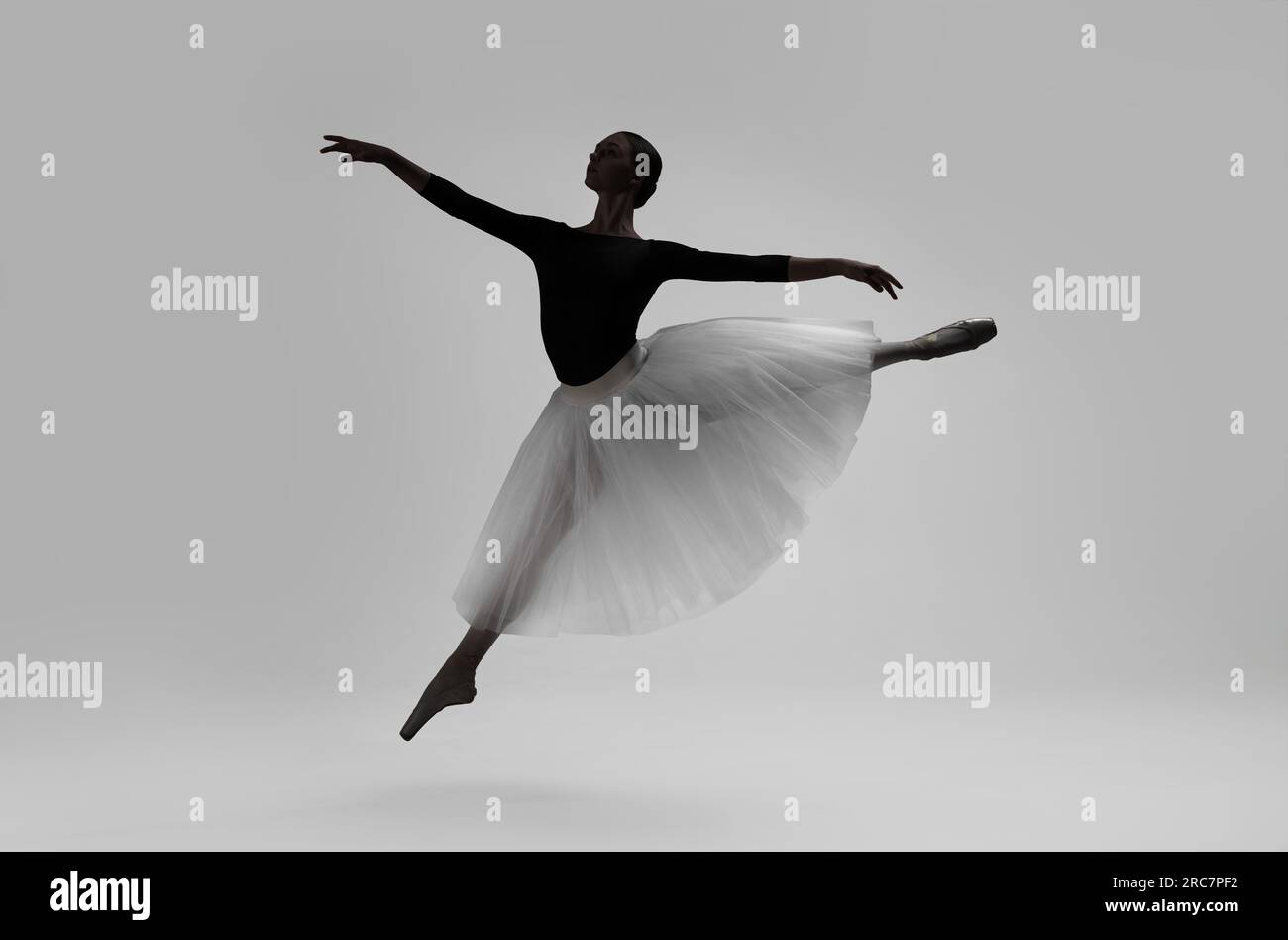 Beautiful ballerina dancing on light grey background. Dark silhouette ...