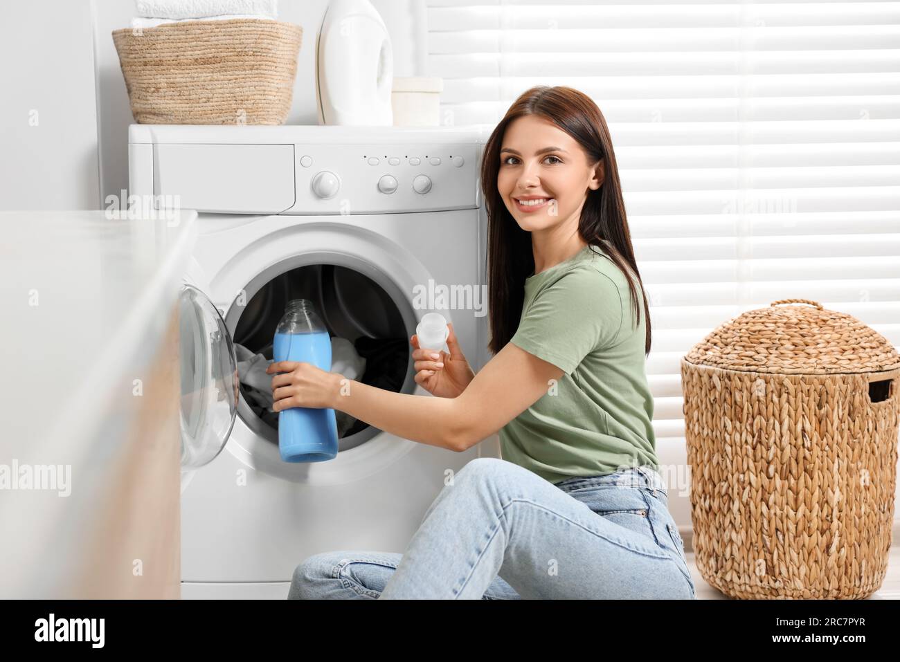 Woman pouring fabric softener into washing machine in bathroom Stock ...