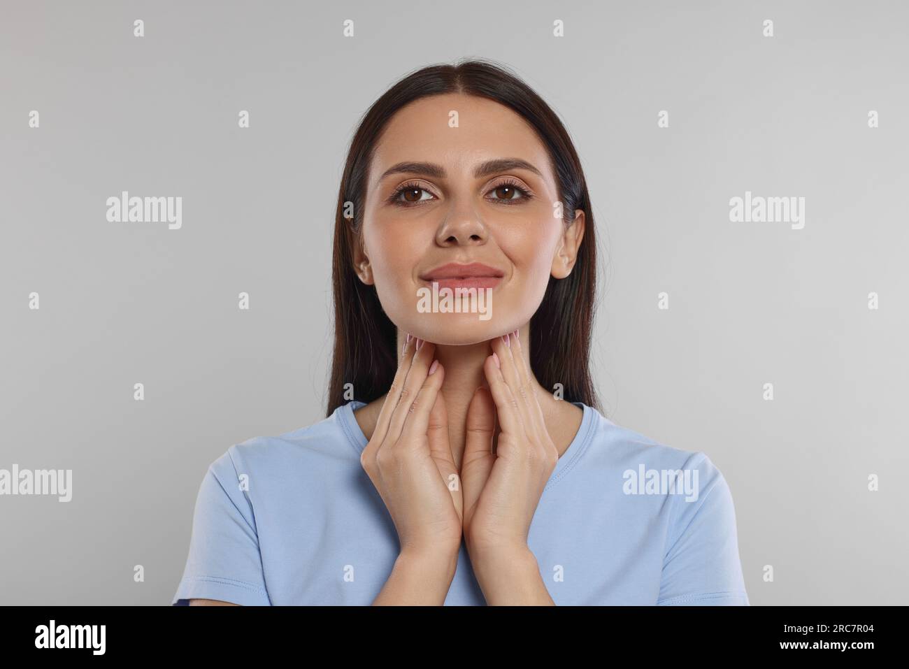 Endocrine system. Young woman doing thyroid self examination on light ...