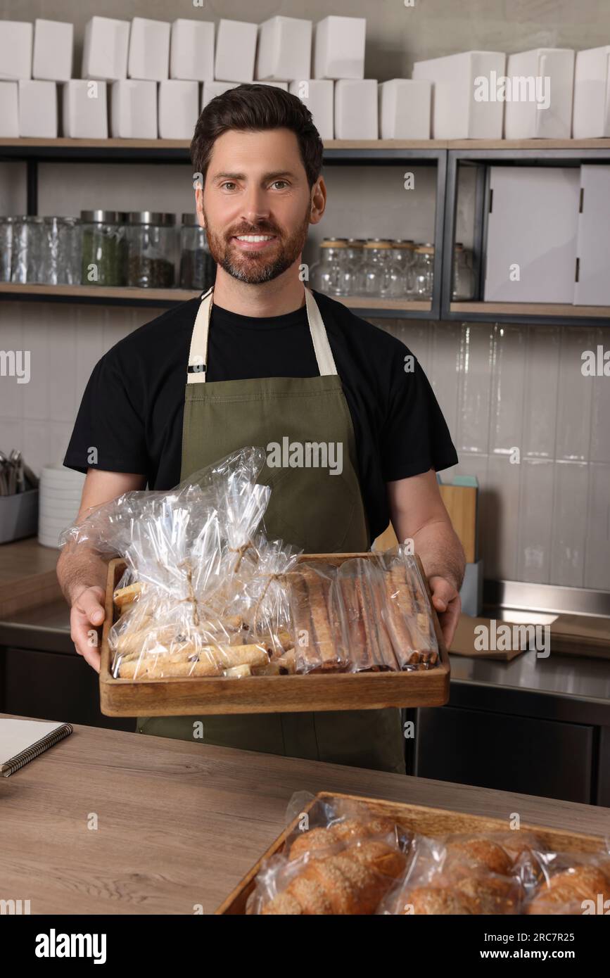 Happy seller with pastries at cashier desk in bakery shop Stock Photo ...