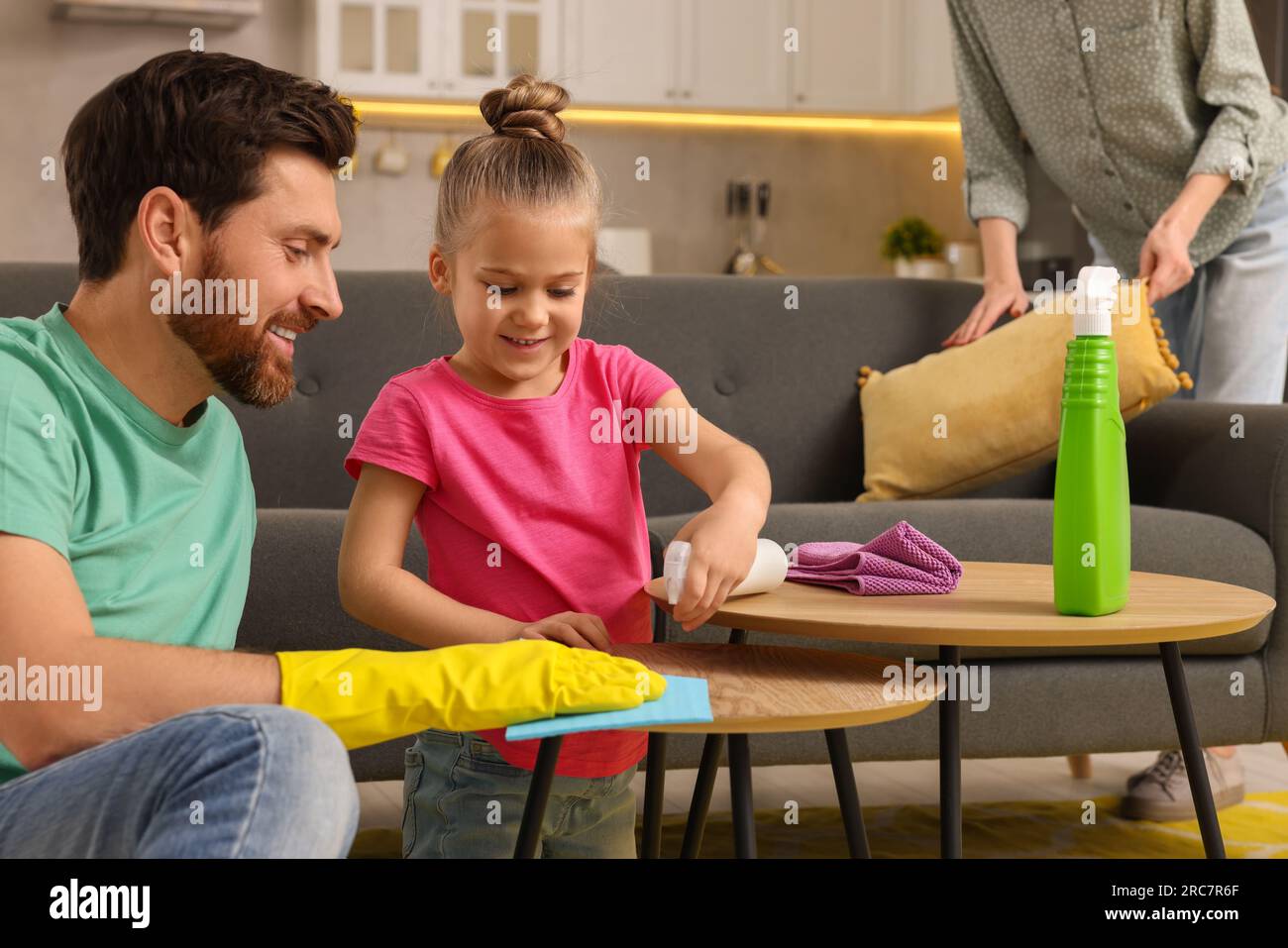 Spring cleaning. Parents with their daughter tidying up living room ...