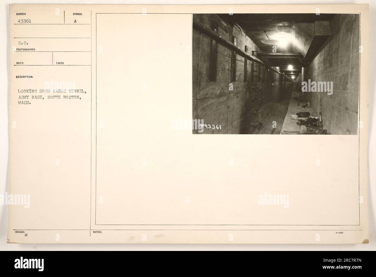 This photograph depicts a soldier looking down a cable tunnel at an ...