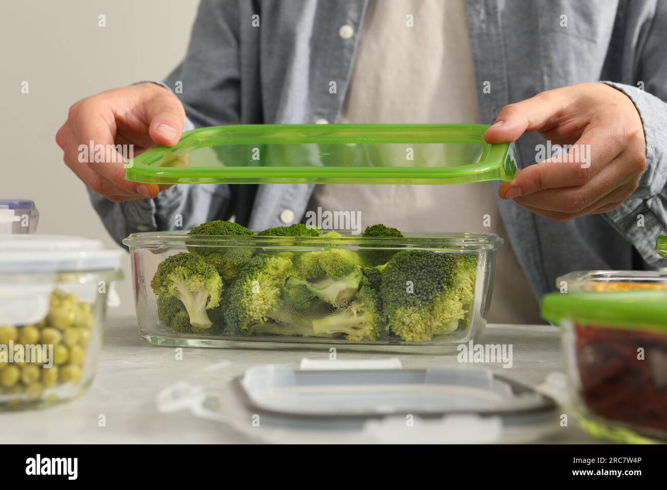 Man closing glass container with lid at light grey marble table in ...