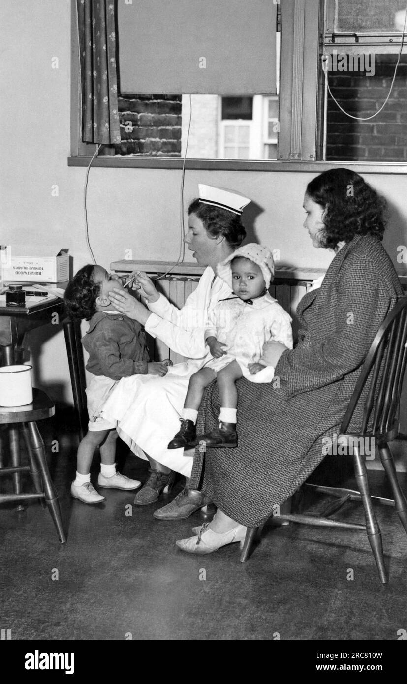 New York, New York: c. 1933. A public school nurse checks the throat of ...