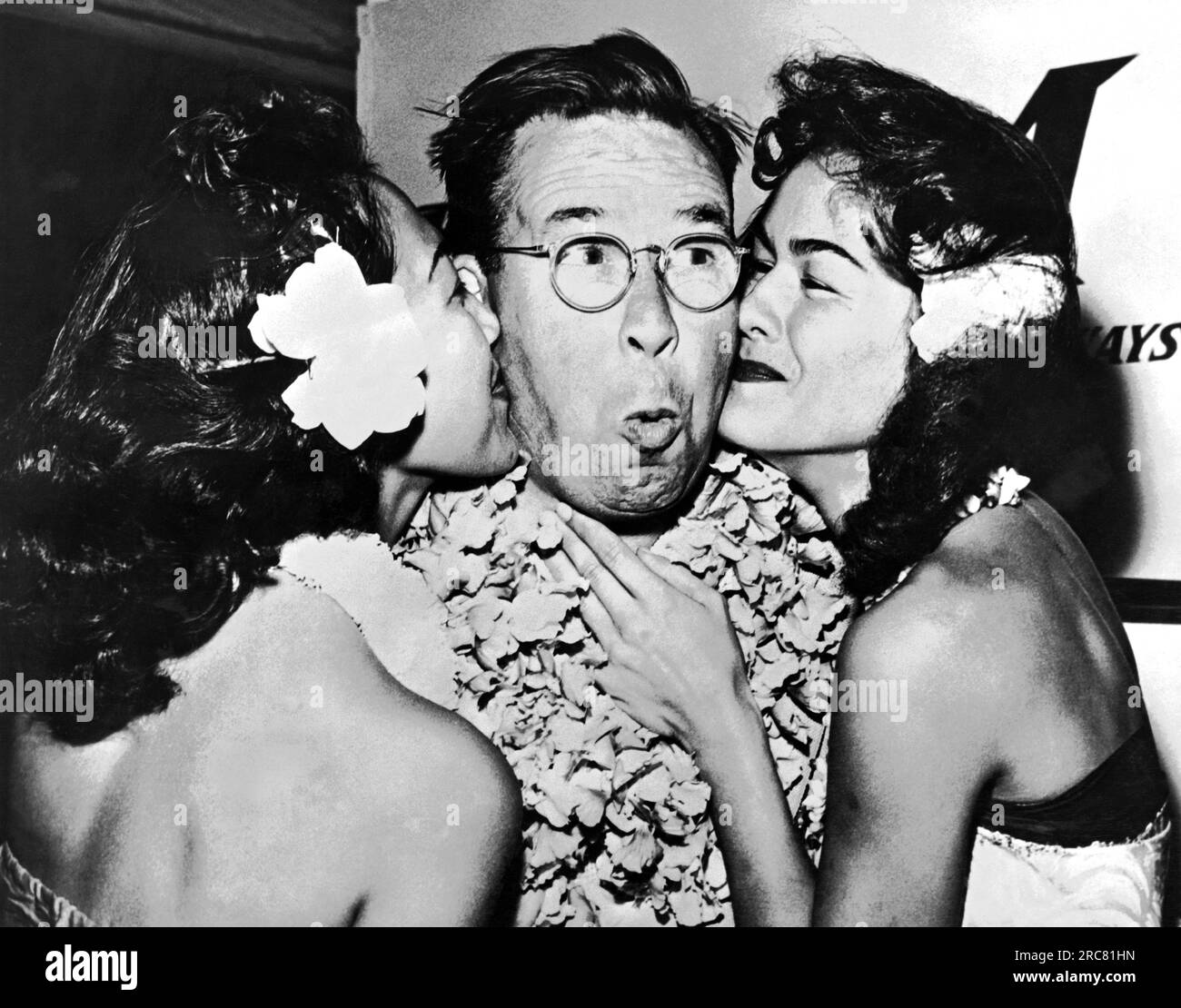 Hawaii: c. 1936 A man is greeted with a lei and kisses bestowed upon ...