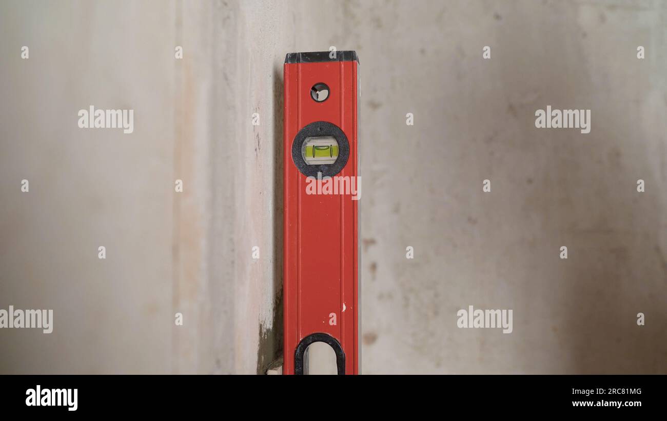 The worker applies a level to the wall. Close-up view of a professional ...