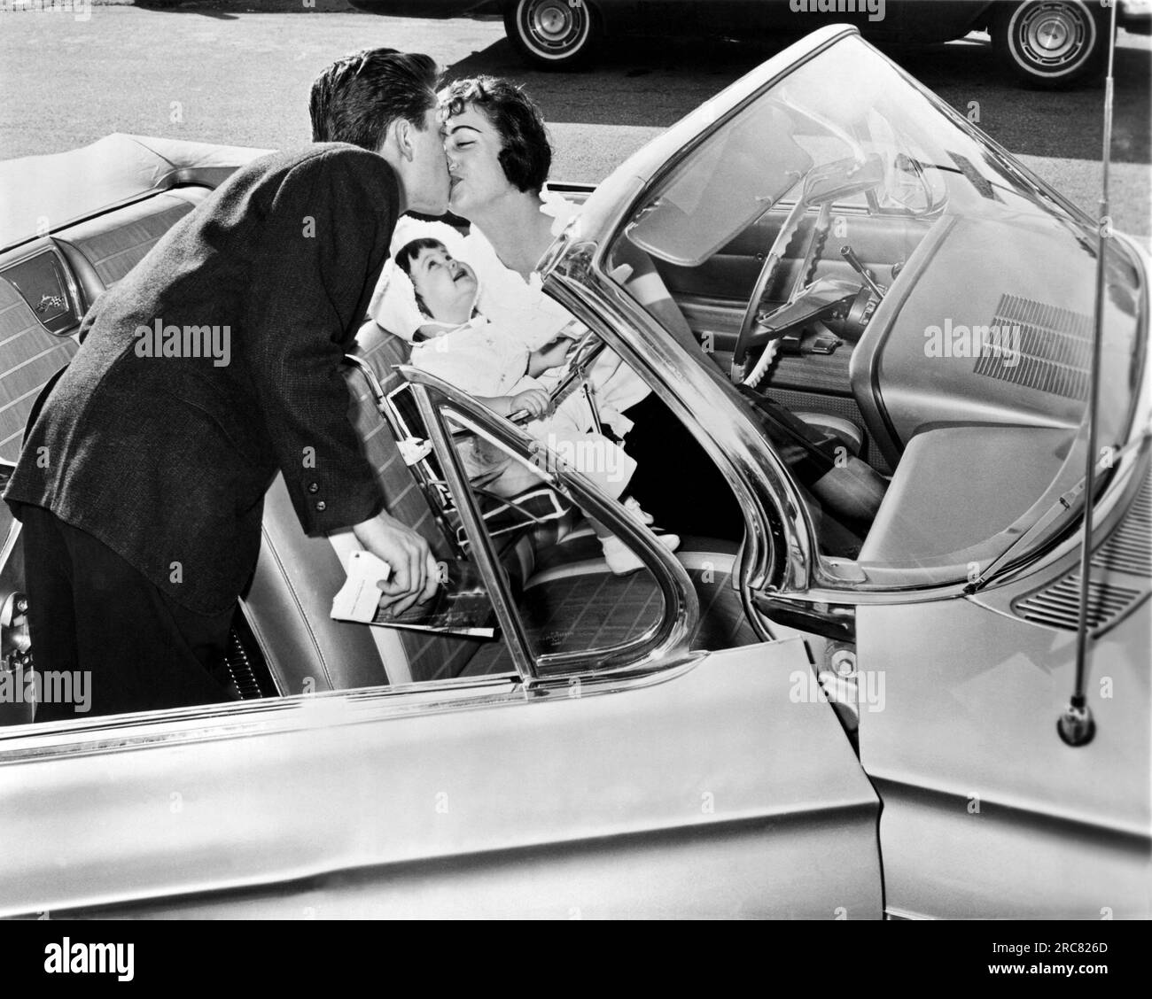 United States: c. 1956. A husband kisses his wife goodby as she drops ...