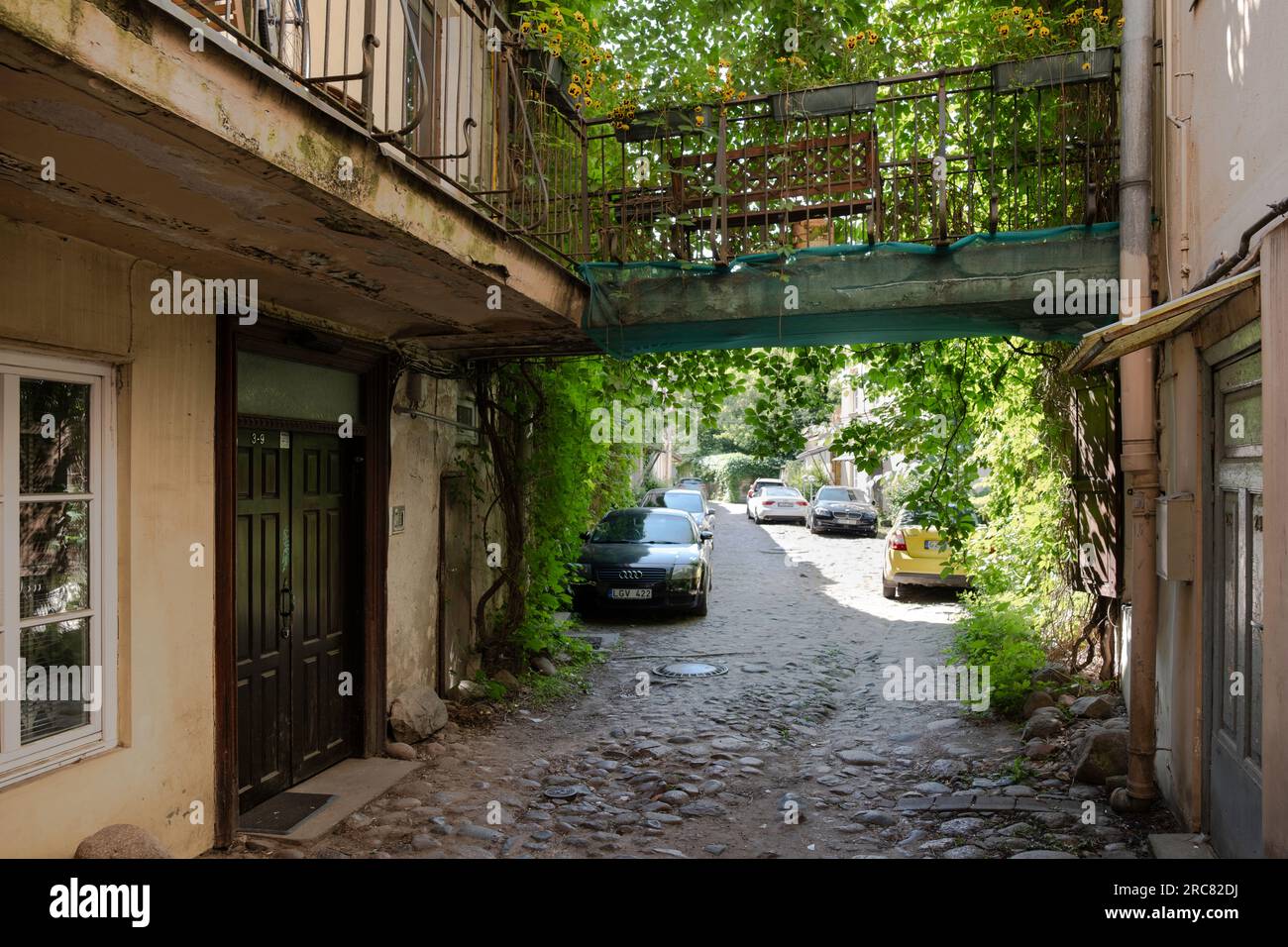 Alley with dilapidated facades of houses on both sides, connected by an ...