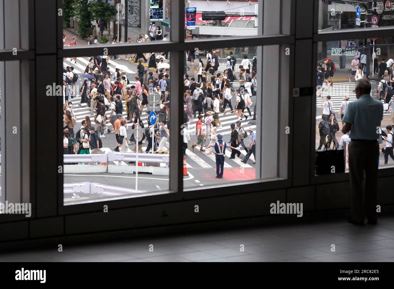People walk cross a pedestrian crossing in Shibuya district under hot ...