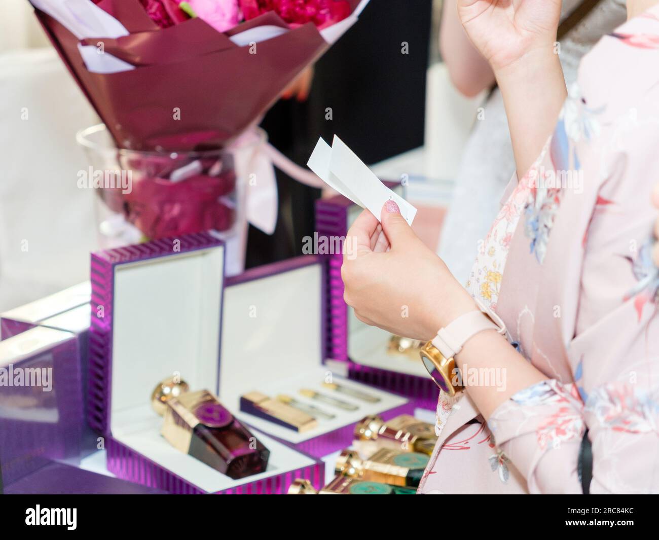 Perfume blotters in a female hand. On a blurred background, bottles ...