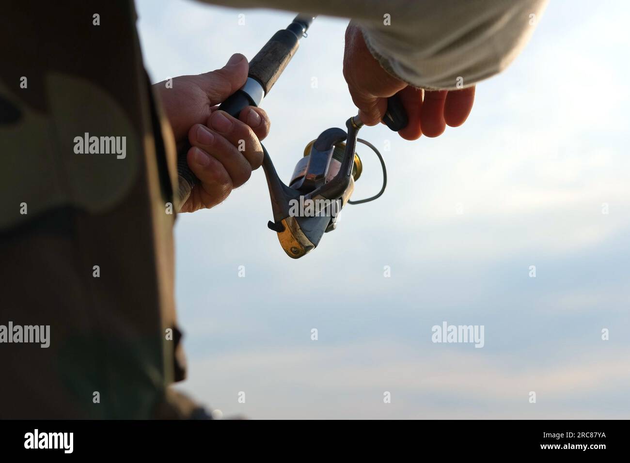 Old man fishing. Senior gray haired fisherman throws a spinning from ...