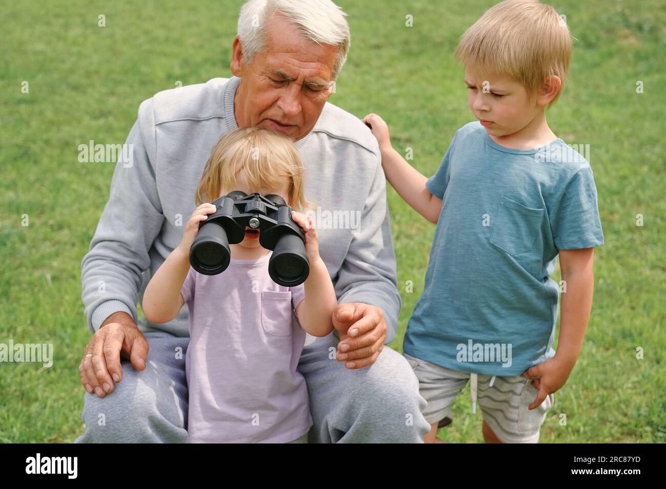 Grandfather and grandchildren using binoculars In Park. Happy family ...