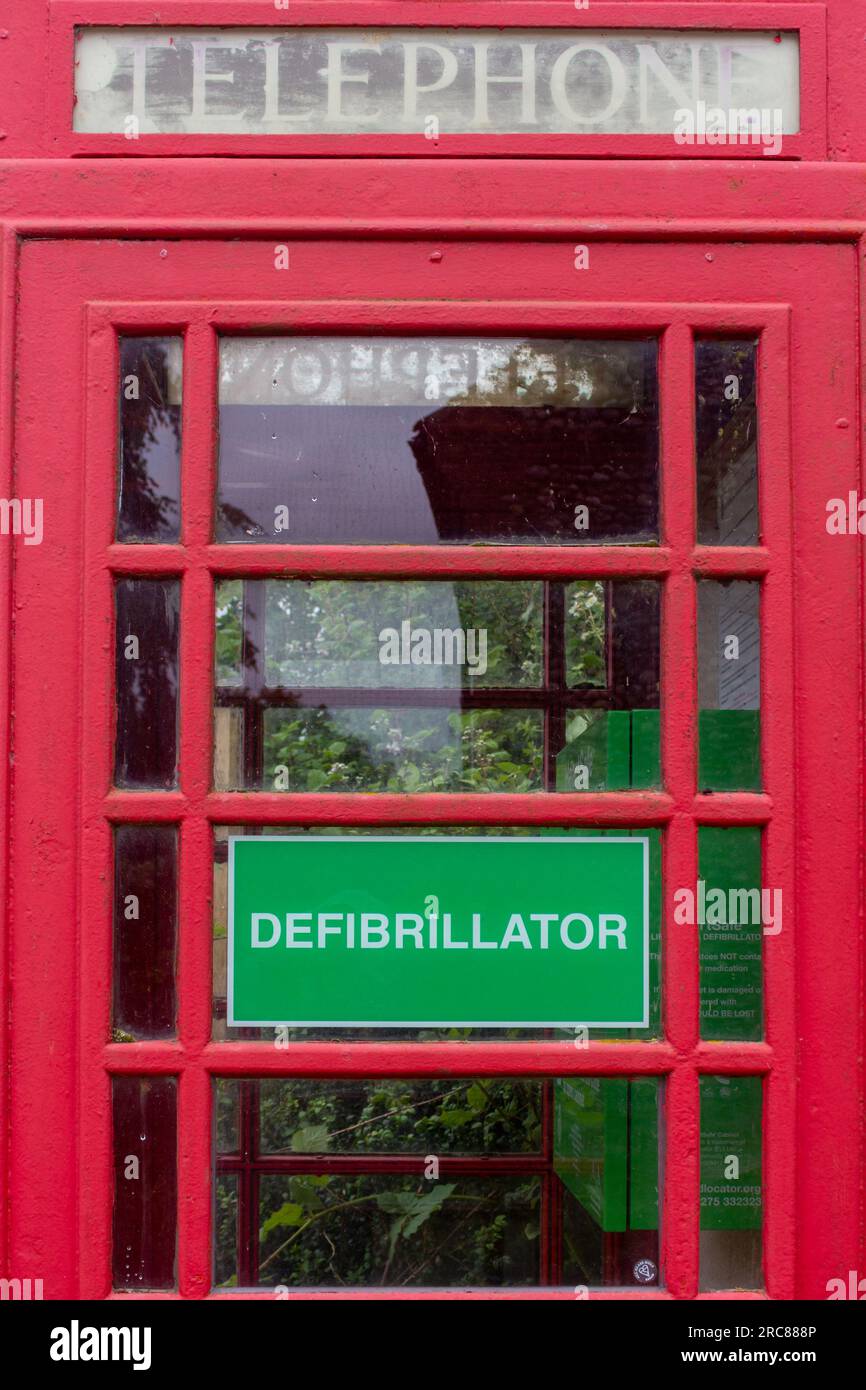 A detail of the front of a red K6 telephone box with a green ...