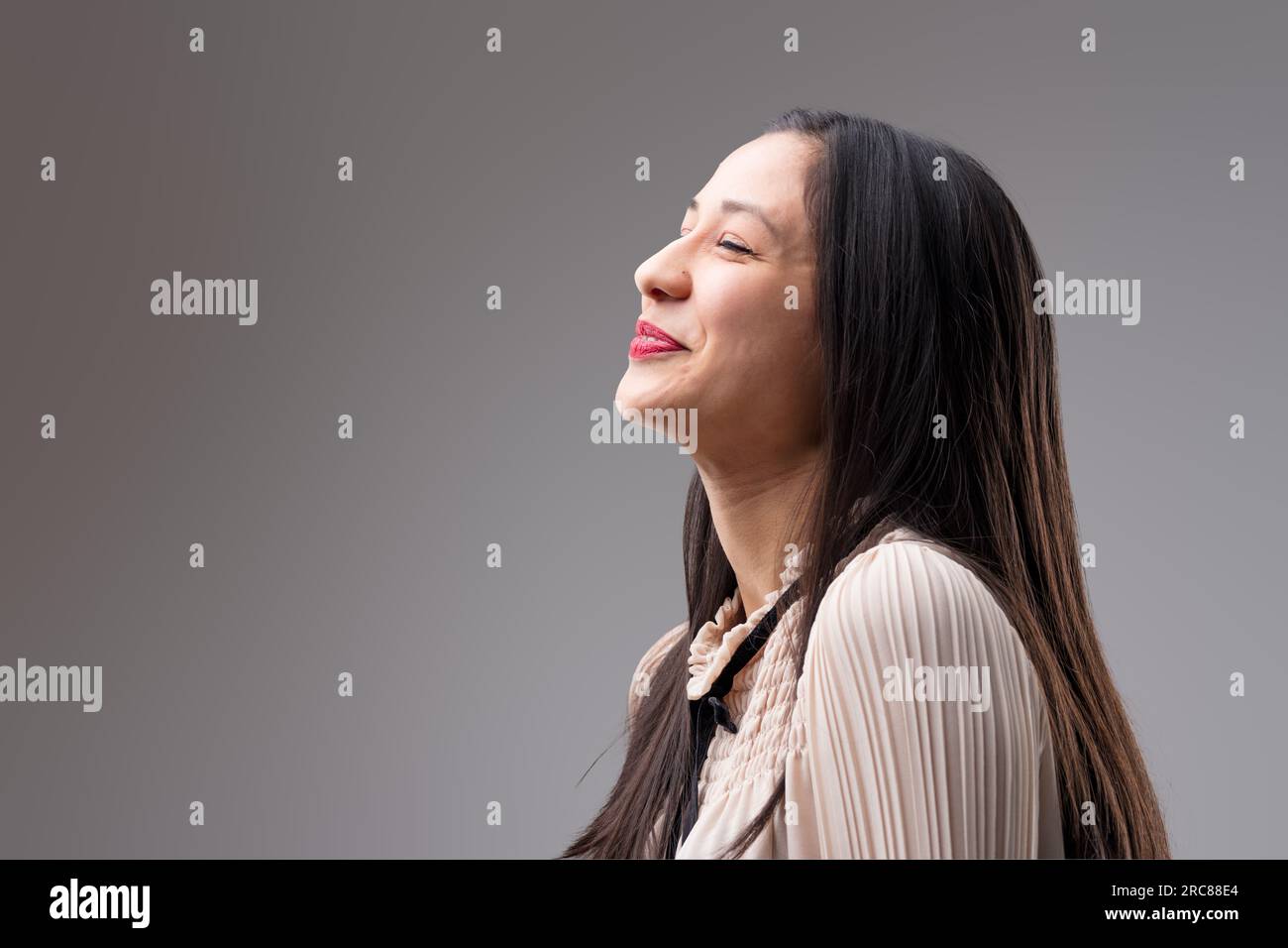 A young woman with long hair looks up left, trying to hold back her ...