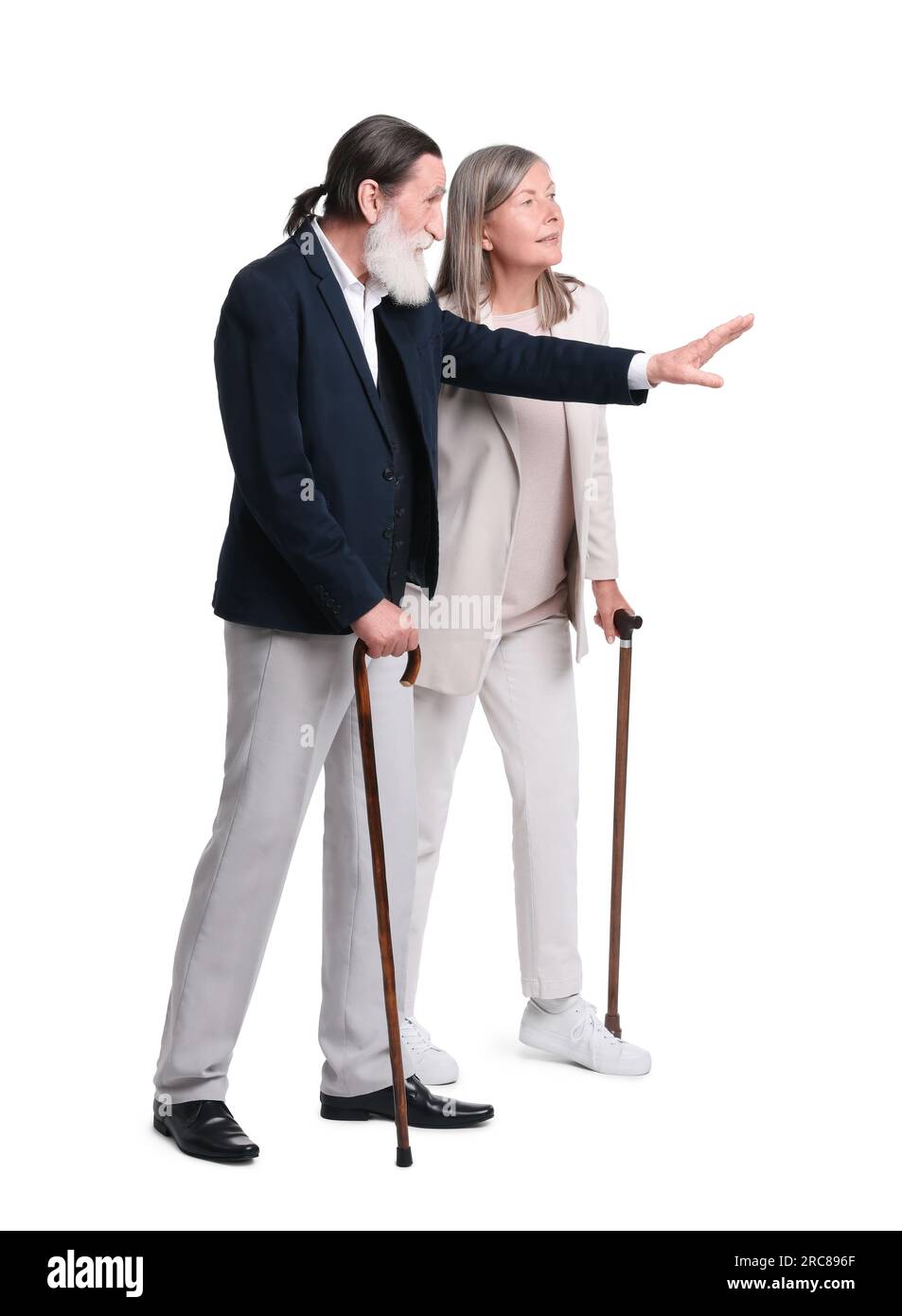 Senior man and woman with walking canes looking at something on white ...