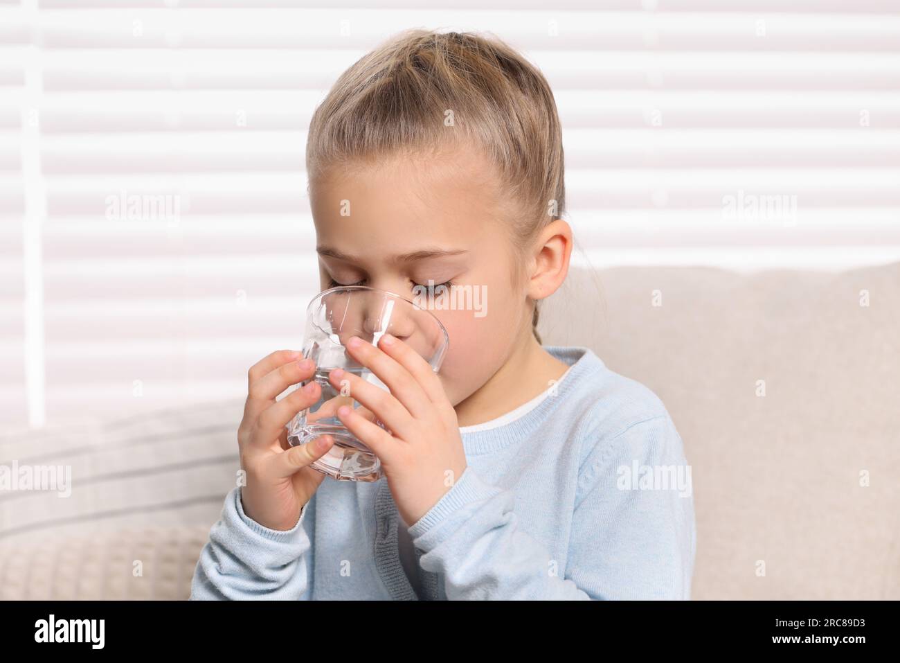 Cute little girl drinking fresh water from glass indoors Stock Photo - Alamy