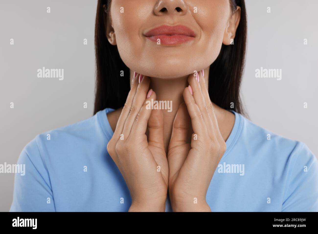 Endocrine system. Woman doing thyroid self examination on light grey ...