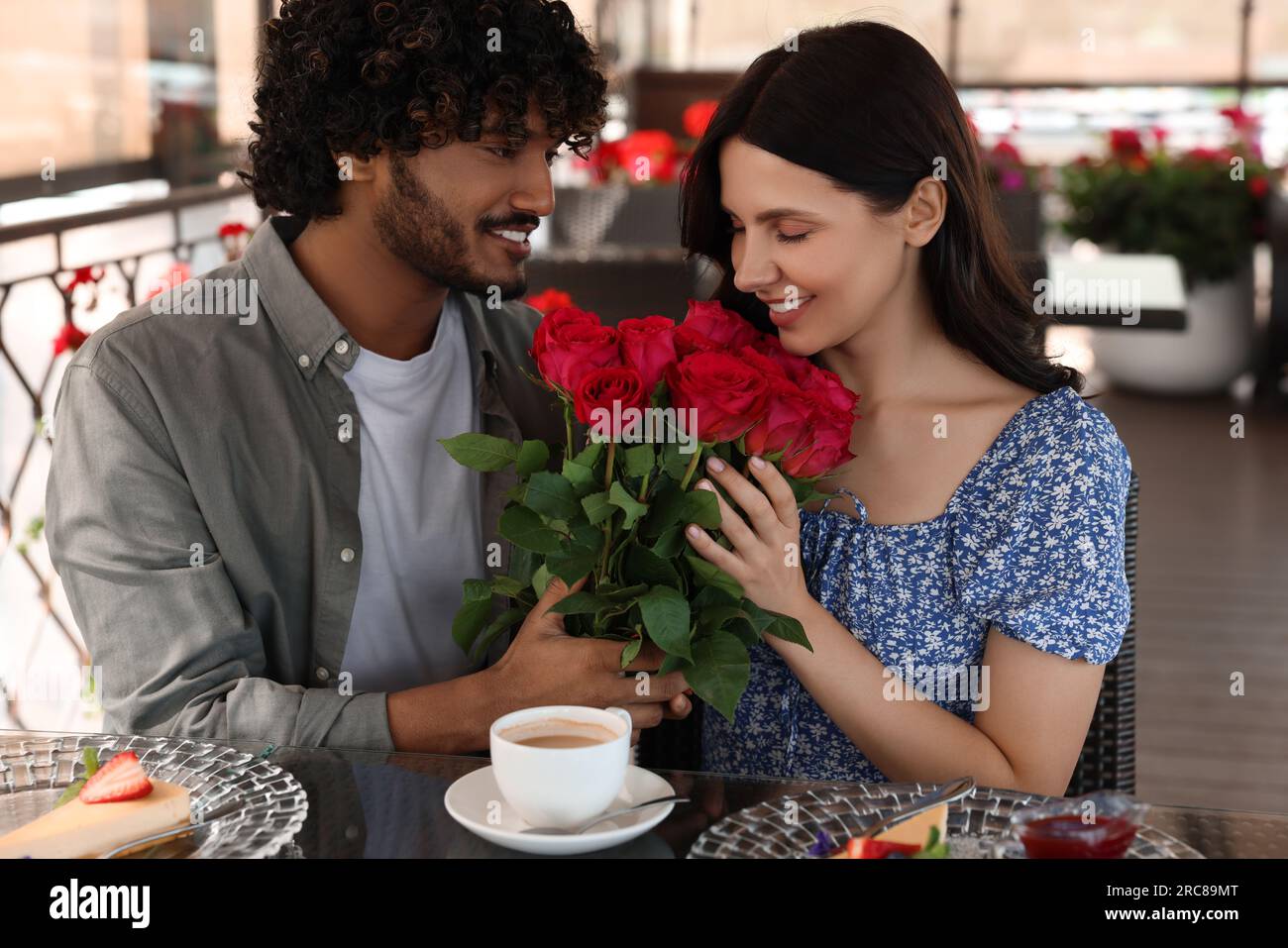 International dating. Handsome man presenting roses to his girlfriend ...