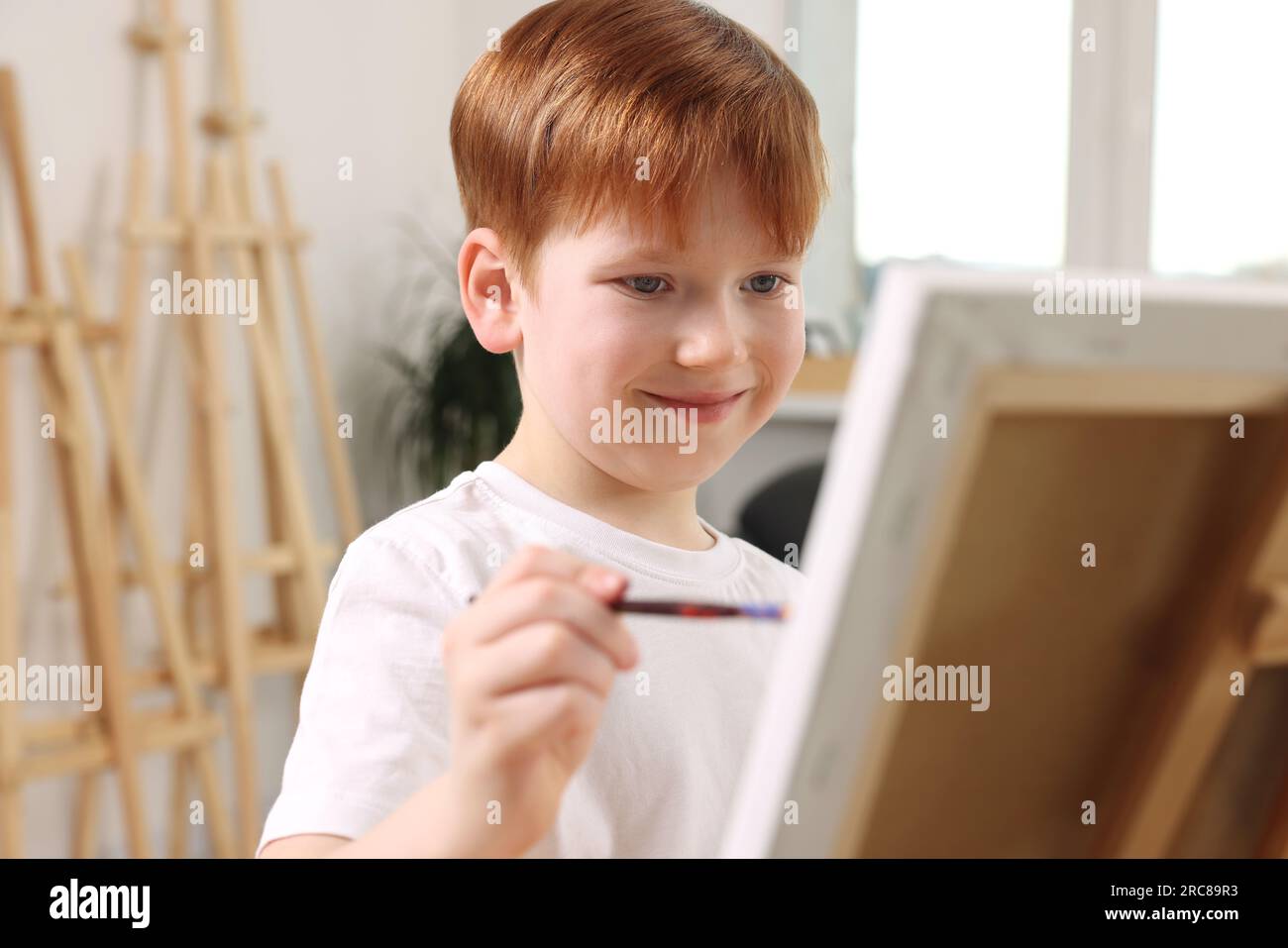 Little boy painting on canvas in studio Stock Photo - Alamy