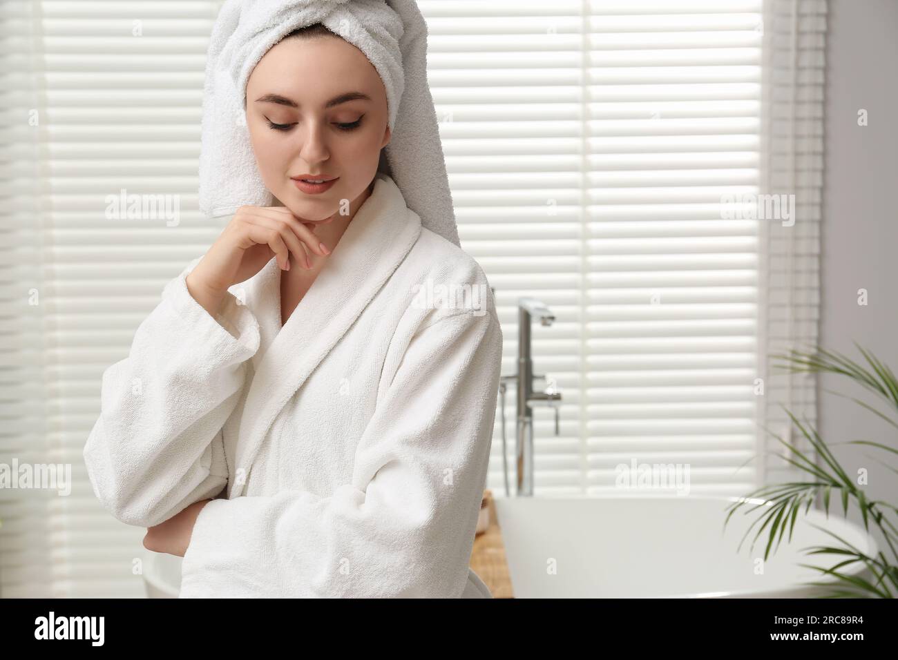 Beautiful woman wearing white robe in bathroom, space for text Stock ...