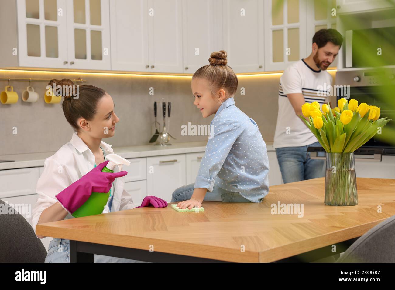 Spring cleaning. Parents with their daughter tidying up kitchen ...